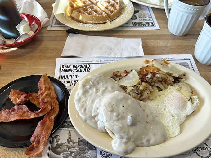 A complete breakfast spread featuring biscuits, gravy, bacon, and hash browns delivers everything your morning needs in one glorious plate.