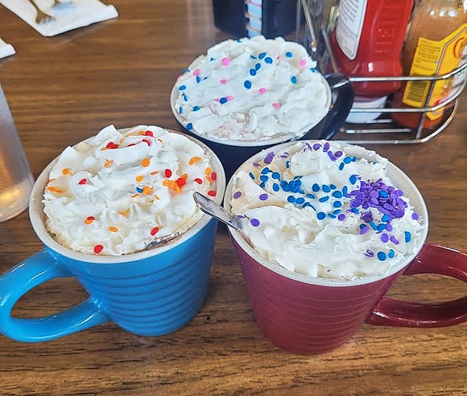 Colorful mugs filled with hot chocolate mountains topped with whipped cream and sprinkles &ndash; childhood joy served regardless of your actual age.
