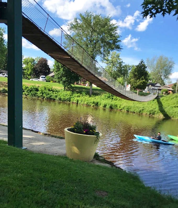Kayakers gain a unique perspective from below, where the bridge's graceful suspension system creates artistic shadows on the water's surface.