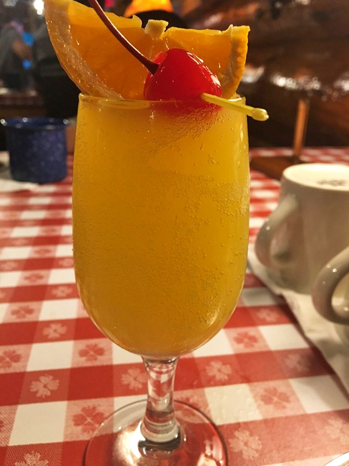 A sunshine-in-a-glass mimosa, garnished with fruit and served in a portion size that says "vacation starts now."