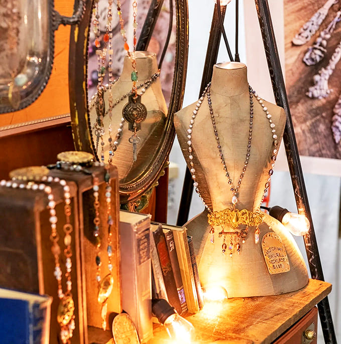 Necklace Display: Vintage mannequin forms showcase handcrafted jewelry against weathered wood, creating a display as artistic as the pieces themselves.