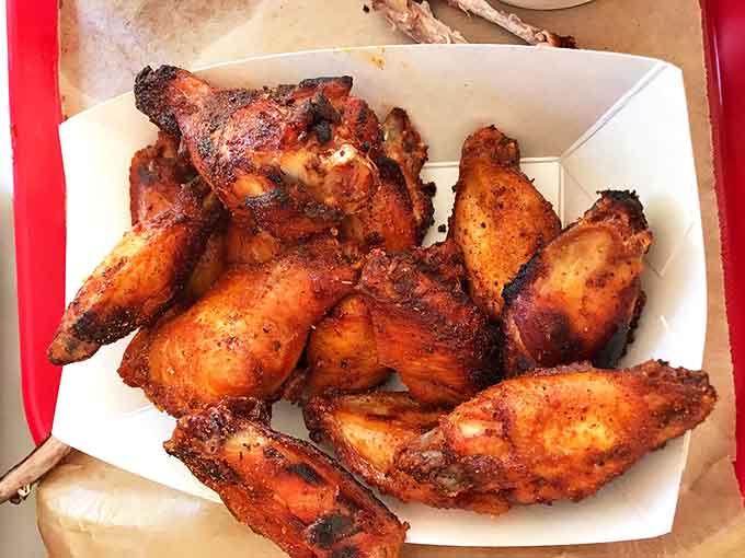 Smoked chicken wings with char-spiced magic prove that barbecue excellence extends beyond the traditional pork and beef offerings.