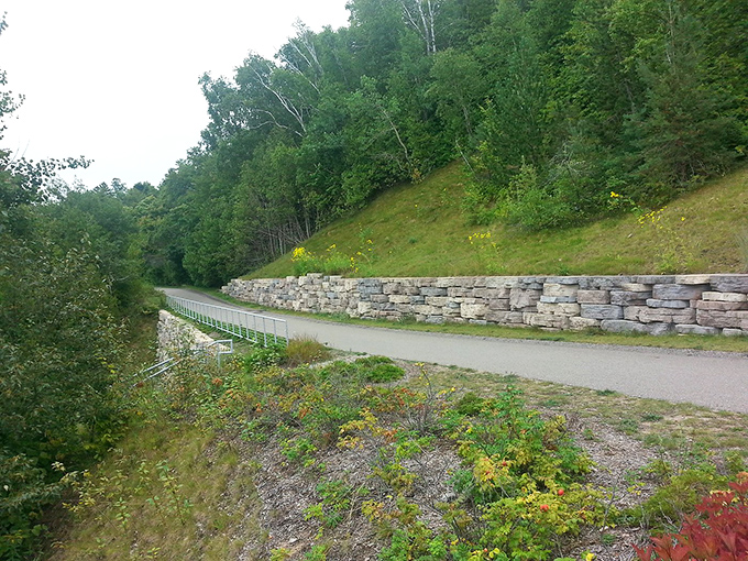 Stone walls cradle the winding path like protective hands, guiding cyclists through landscapes shaped by glaciers and human determination.