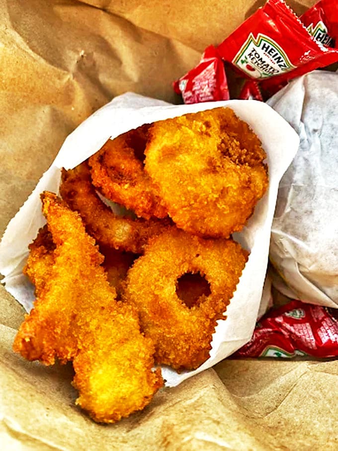 Golden onion rings that shatter with satisfying crunch, revealing sweet tender onion inside that makes you reconsider your relationship with french fries.