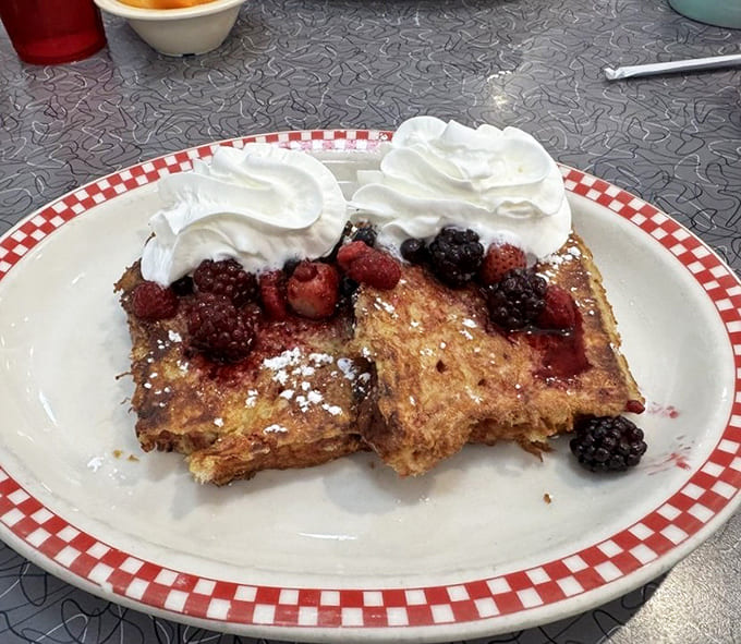 Triple berry French toast that blurs the line between breakfast and dessert &ndash; a sweet morning symphony topped with clouds of whipped cream.
