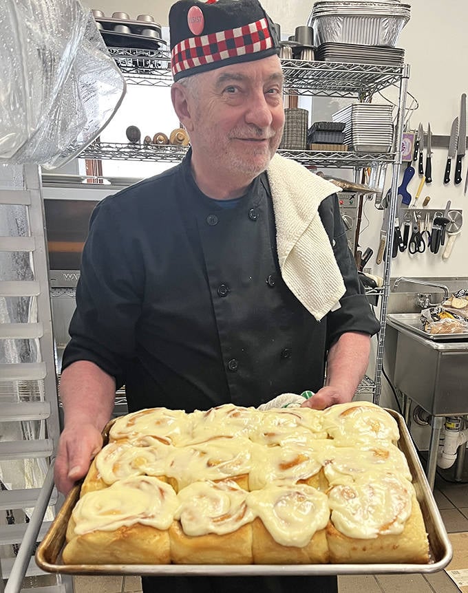 The wizard behind the curtain &ndash; a skilled baker proudly displays freshly made cinnamon rolls that smell like heaven and taste even better.