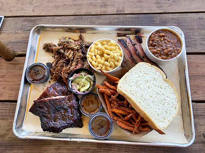 A barbecue platter that dreams are made of &ndash; multiple meats, sides, and sauces creating a symphony of flavors on a single tray.