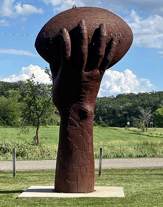Touchdown for creativity! This giant hand clutching a football freezes a moment of victory in metal, celebrating America's favorite game.