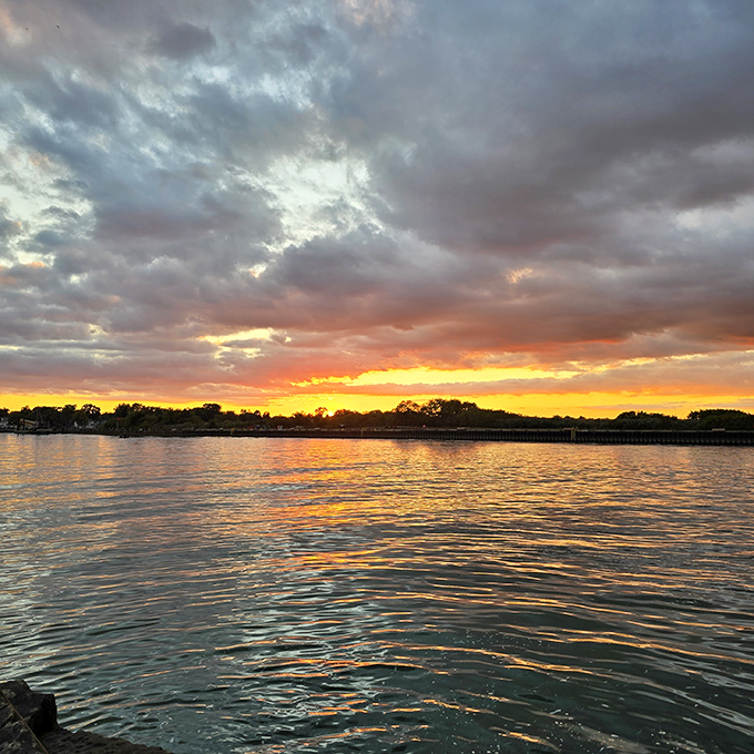 Nature's nightly light show paints the sky in fiery hues, reflecting off the water in a double feature of beauty.