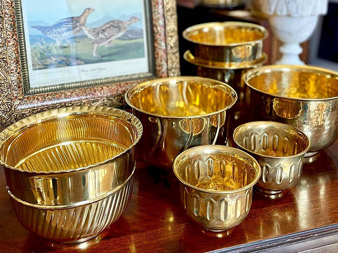 These gleaming brass vessels once graced formal dining tables, their warm golden tones practically radiating stories of celebrations past.