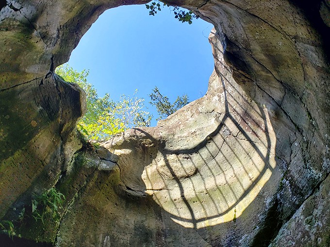 Looking up from inside Earth's ancient memory, where sky peeks through a natural skylight carved by forces older than human history.