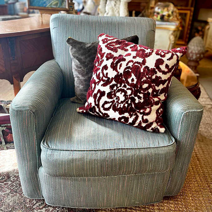 A mid-century armchair upholstered in soft blue fabric offers a moment of respite during your treasure hunt &ndash; note the perfect accent pillow.
