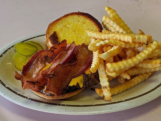 The bacon cheeseburger arrives with crispy crinkle-cut fries and pickles – proof that sometimes the classics are classics for good reason.