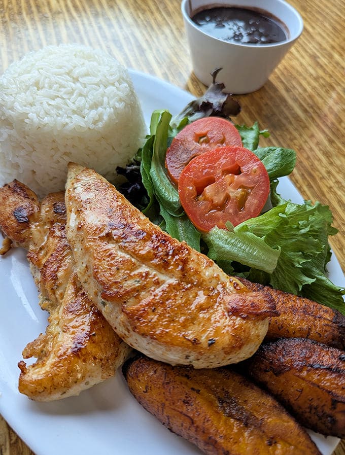 The Bistec de Pollo arrives like a postcard from Havana – perfectly grilled chicken alongside rice, beans, plantains and fresh greens.