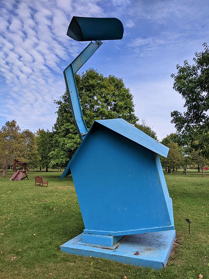 A bold blue sculpture challenges gravity with its tilted form, creating a sense of dynamic movement despite being perfectly still.