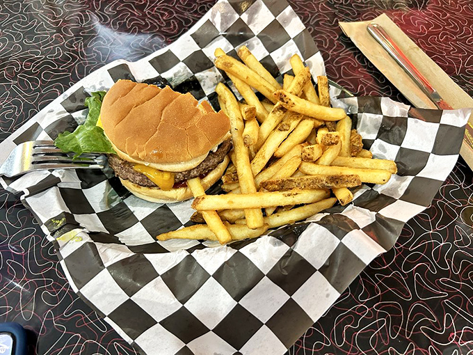 This isn't just any cheeseburger – it's a hand-formed patty of beefy perfection nestled on a toasted bun with golden fries standing by for dipping duty.