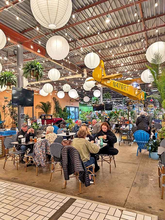 A European-inspired oasis where shoppers pause with craft beers and lattes, surrounded by plants and paper lanterns.