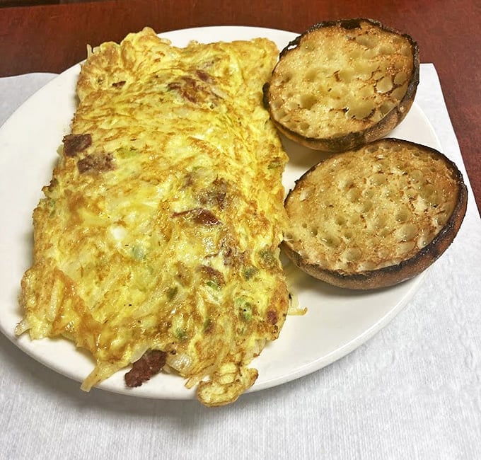 Breakfast architecture at its finest &ndash; a golden egg blanket wrapped around savory fillings, with English muffins standing guard.