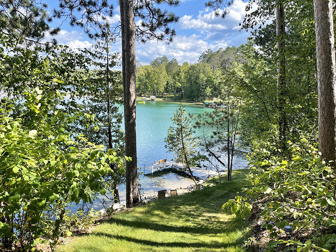 Morning light filters through towering pines, creating dappled patterns on Deer Lake's crystal-clear shoreline &ndash; nature's own stained glass.