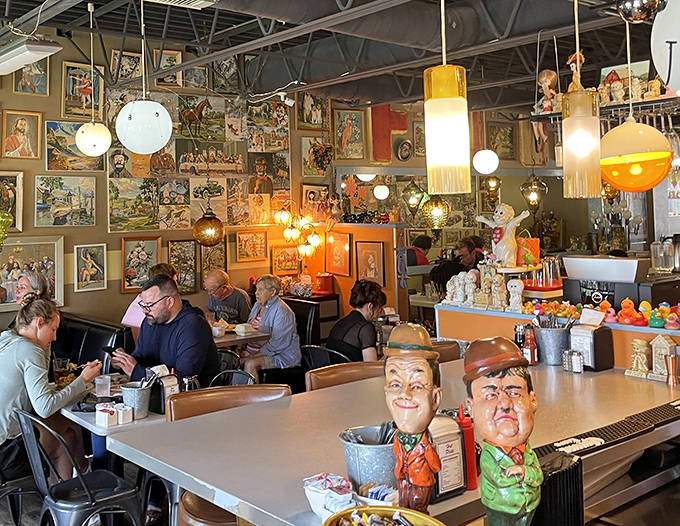 The dining room buzzes with conversation as patrons feast amid walls of vintage artwork. Every table tells a different story in this breakfast theater.