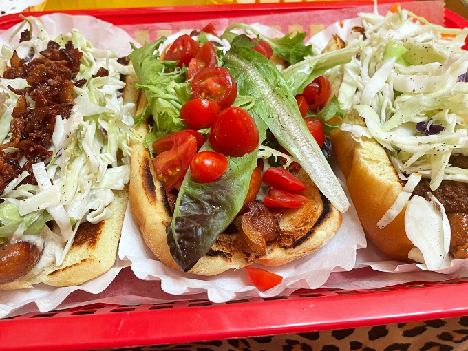 A trio of hot dogs dressed to impress. That middle one with fresh tomatoes and lettuce is practically wearing a garden&mdash;fast food with a farmer's market upgrade.