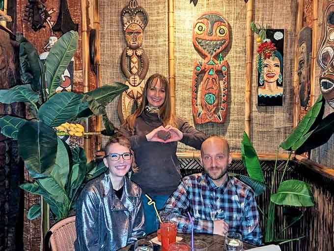 Happy patrons enjoy the immersive tiki experience surrounded by authentic Polynesian decor—proof that paradise exists in unexpected places.