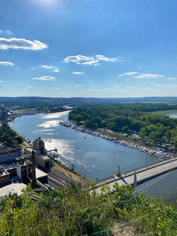 The Mississippi River glitters like a silver snake from this height, with boats leaving delicate white trails in their wake.