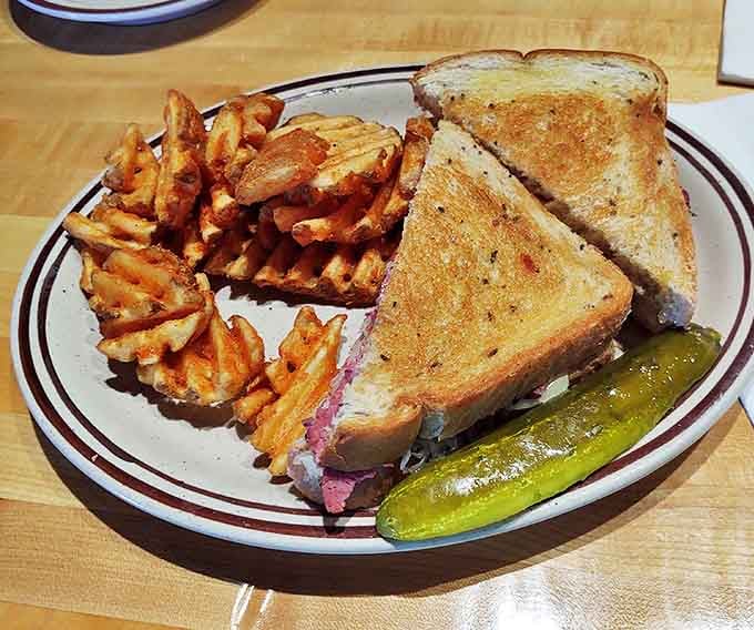 The Reuben sandwich stands tall like a control tower, layers of corned beef and sauerkraut creating a savory skyline of flavor.