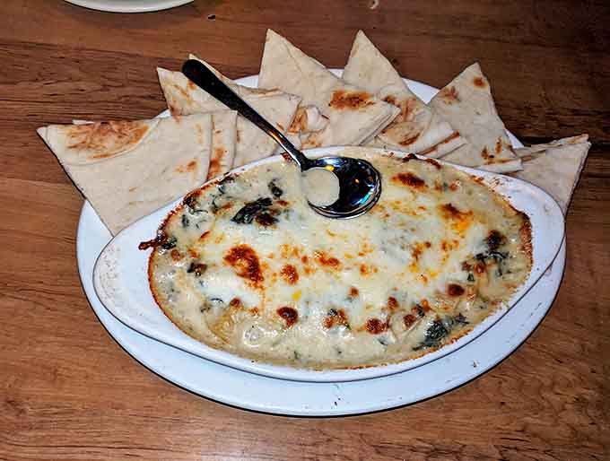 Spinach artichoke dip bubbling with molten cheese goodness &ndash; where "sharing" becomes a concept you'll quickly reconsider after the first bite.