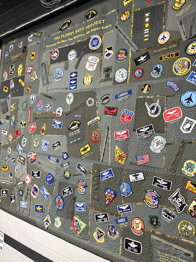 Military patches and insignia cover this display like a quilt of service, each one representing a unit, mission, or achievement that contributed to America's aviation heritage and military strength.