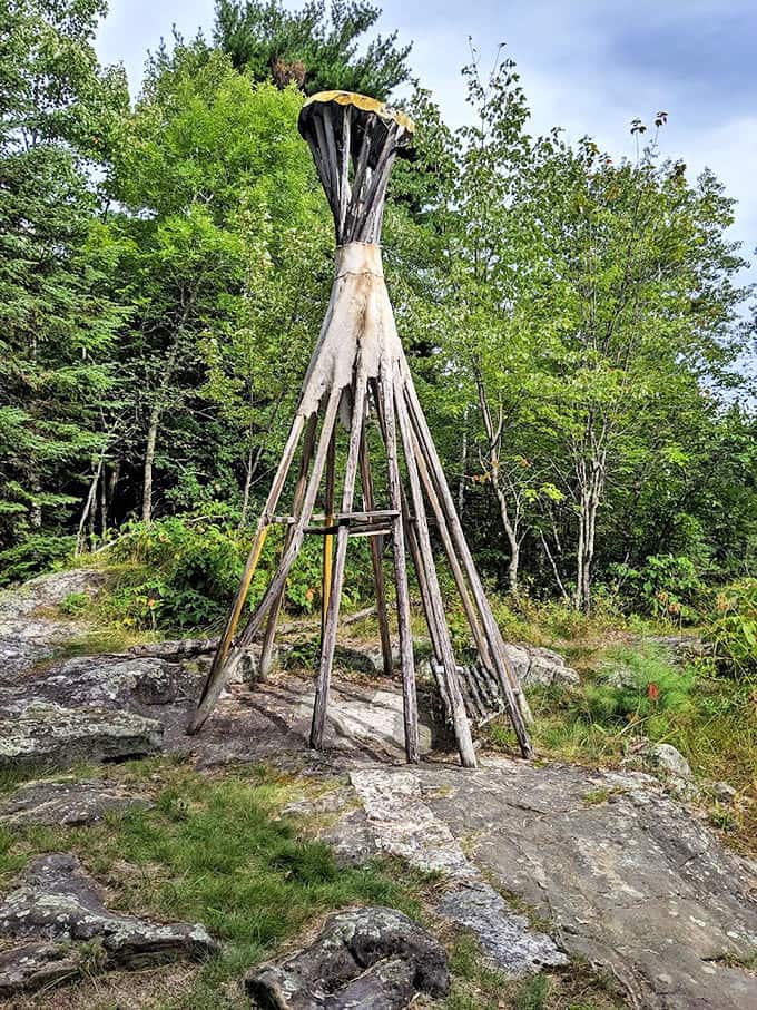 This teepee-like wooden sculpture adds vertical drama to the landscape, its weathered poles reaching skyward like a primitive sundial marking time's passage.