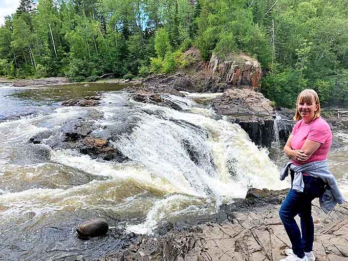 Joy at the edge of wilderness: A visitor enjoys the smaller cascades along the Pigeon River, where nature's playground invites exploration.