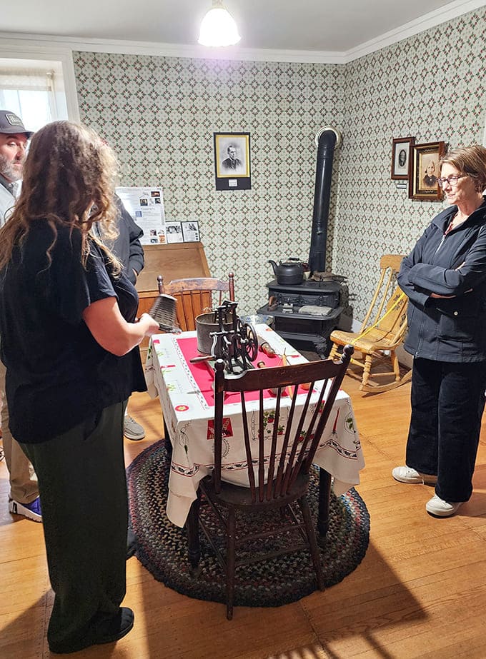 Visitors enjoy an interactive tour, learning about local history while gathered around a vintage stove in the authentic kitchen.