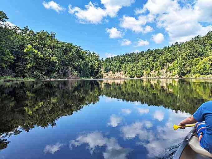 Mirror-like waters double the beauty, reflecting both sky and forest in a natural masterpiece that changes with every passing cloud.