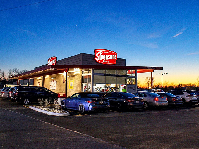 As darkness falls, Swensons transforms into a glowing oasis of comfort food, its illuminated sign beckoning hungry travelers like a lighthouse for burger enthusiasts.