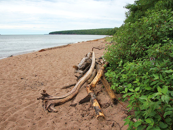 Sandy shores provide a gentle contrast to the dramatic red cliffs, perfect for a post-hike cooldown in Lake Superior's refreshing waters.