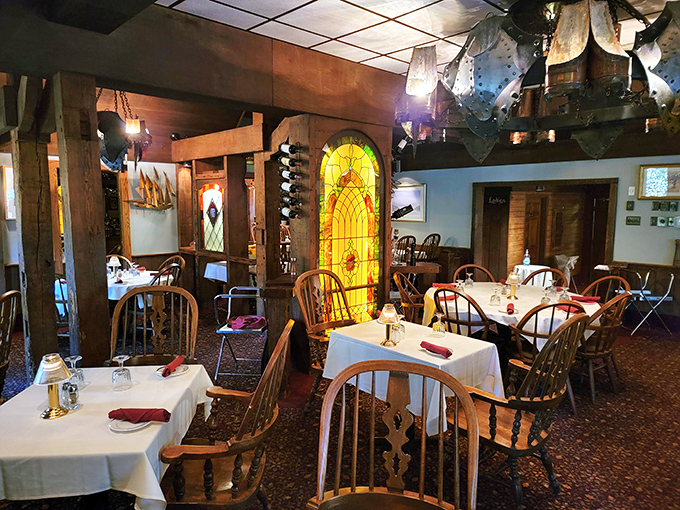 Stained glass windows cast colorful patterns across the dining room, where Windsor chairs and white tablecloths create an atmosphere of casual elegance.
