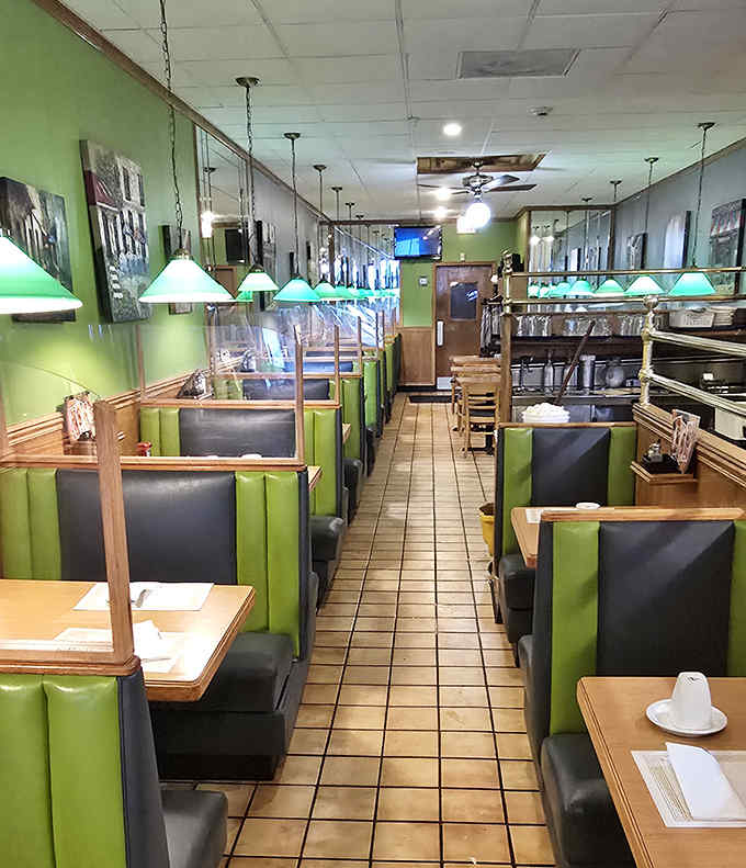 The dining area stretches back like a green-hued tunnel of breakfast possibilities, each booth promising its own morning adventure.