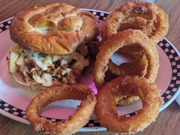 A sandwich creation served with golden onion rings &ndash; comfort food that hugs your soul while challenging your jaw's maximum opening capacity.