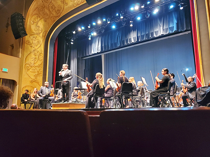 The conductor's raised baton freezes a moment of anticipation as the orchestra waits to fill the historic space with symphonic splendor.