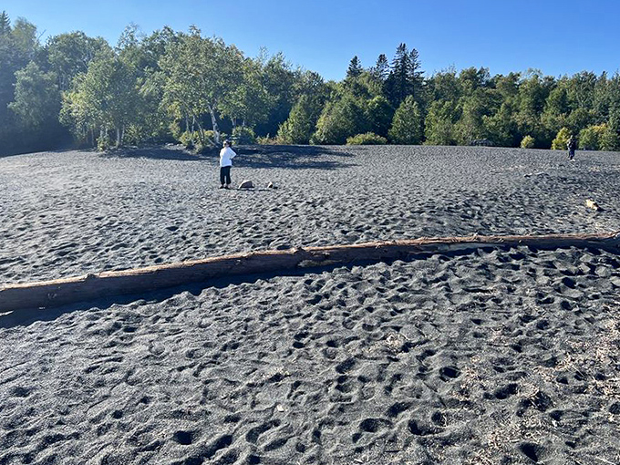 The beach's expansive sandy stretches invite contemplative walks where each step sinks slightly into the velvety dark surface beneath.