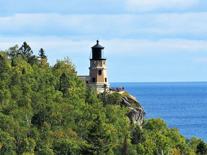 Hikers pause to appreciate the lighthouse from this perfect vantage point. The combination of forest, cliff, and historic structure creates an almost surreal Minnesota landscape.