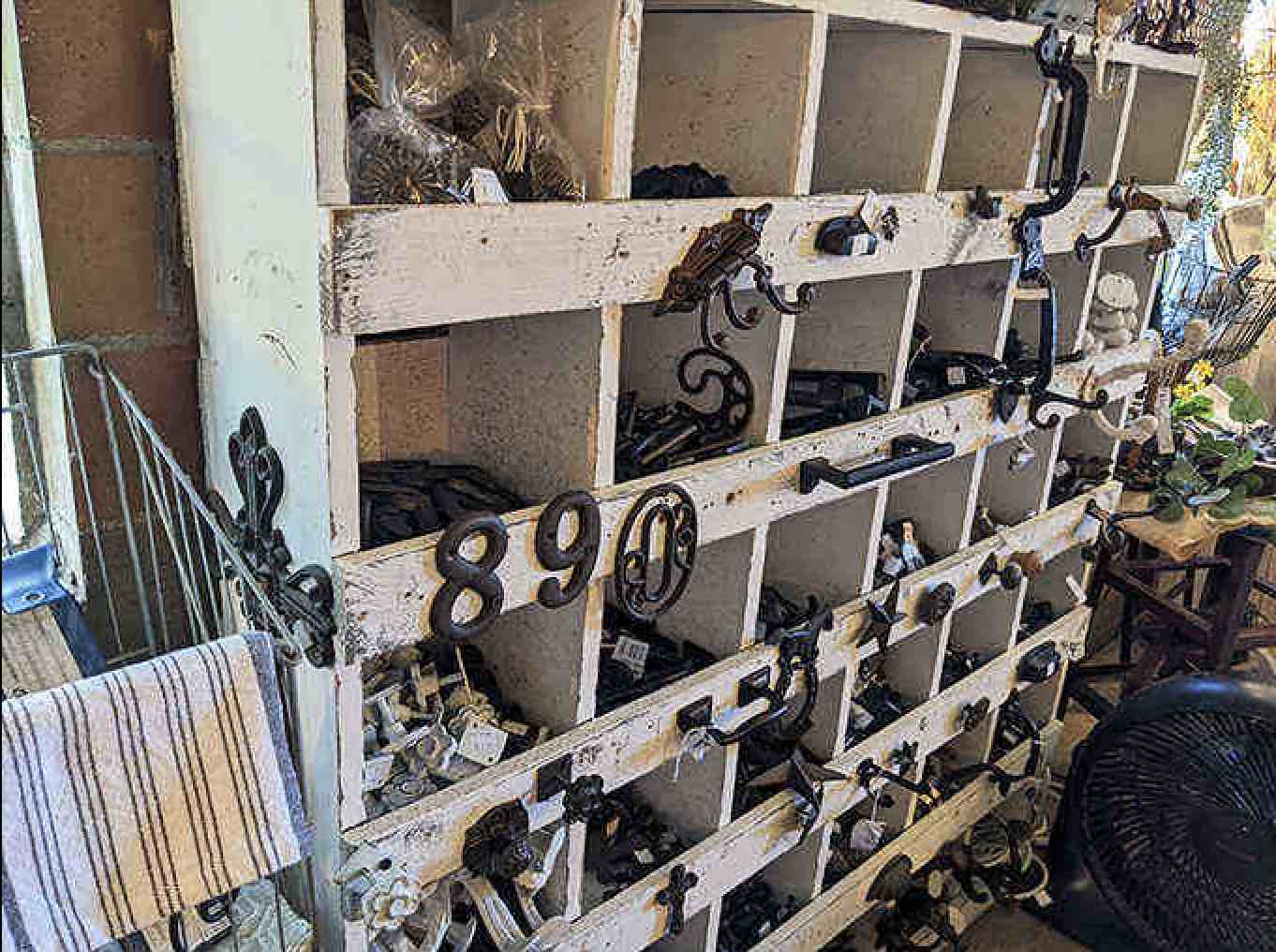 A collection of cast iron hooks and hardware awaits new homes, their numbered cubbies organizing bits of history that could add character to any space.