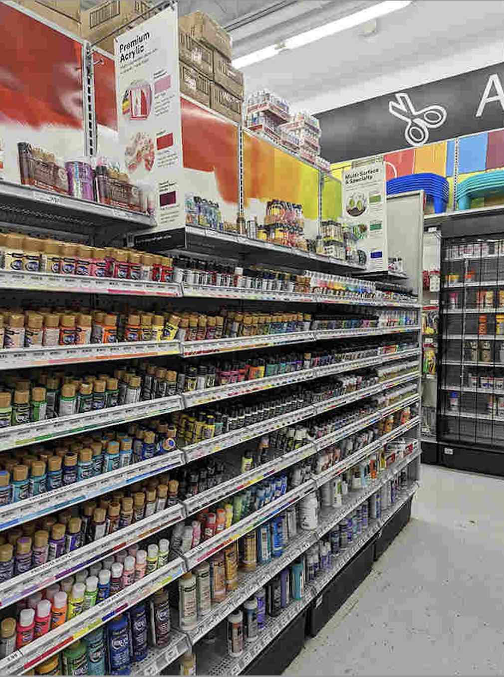 A kaleidoscope of acrylic paints lines the shelves, each bottle a universe of possibility waiting to transform blank canvas into vibrant art.