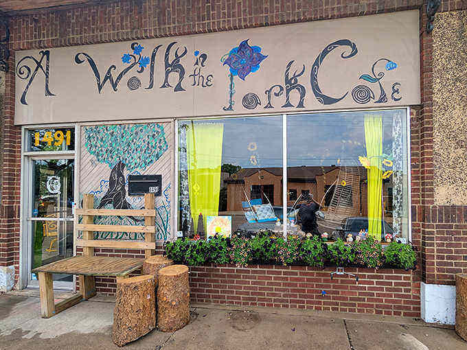 The whimsical storefront of A Walk in the Park Cafe beckons with its artistic sign and tree stump seating, promising an experience beyond ordinary breakfast.