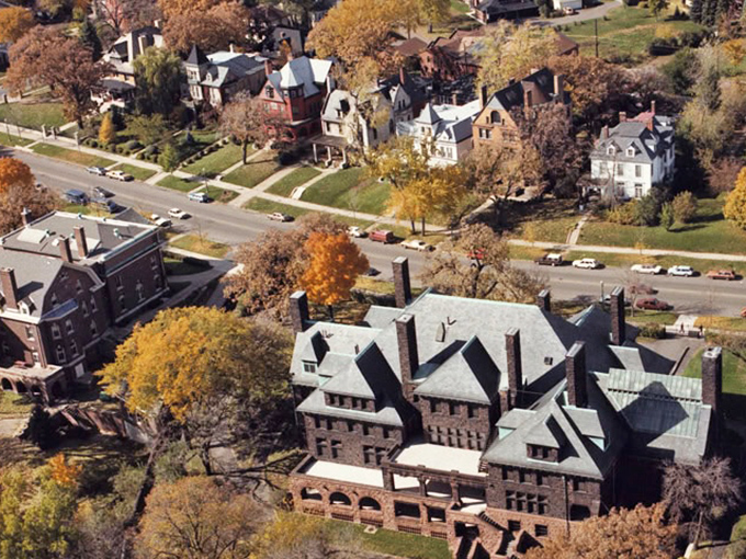 Aerial view of Summit Avenue's magnificent Victorian mansions nestled among autumn foliage – Minnesota's architectural runway where history struts its stuff.