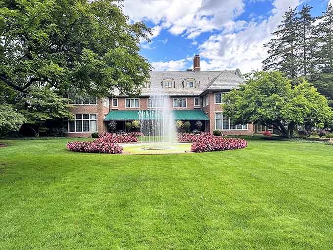 The stately Applewood Estate mansion stands proudly with its fountain centerpiece, a brick masterpiece framed by meticulous gardens and Michigan sky.
