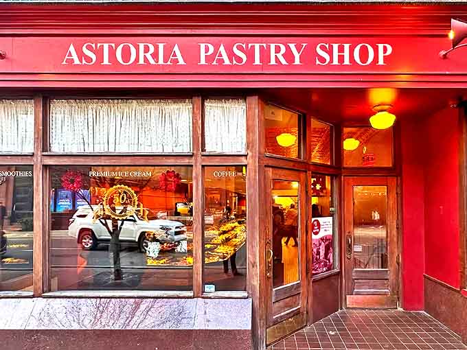 The vibrant red storefront of Astoria Pastry Shop beckons like a beacon of sweetness in Detroit's Greektown, promising old-world delights within.