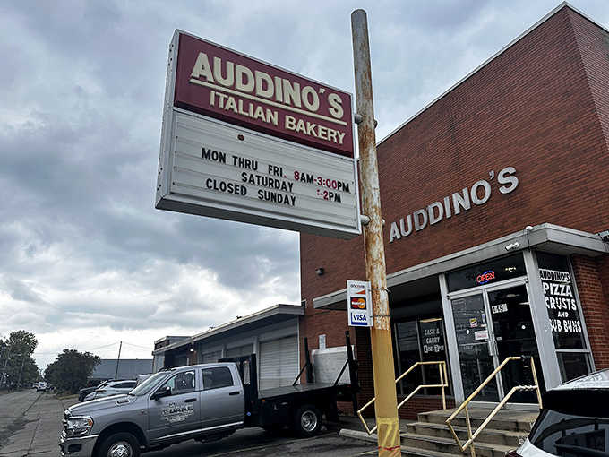 The iconic red Auddino's sign stands sentinel against cloudy skies, promising Italian delights within these brick walls since generations before Instagram existed.
