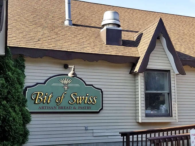 The charming exterior of Bit of Swiss beckons with its distinctive A-frame roof and welcoming sign &ndash; a portal to European pastry paradise in Michigan.